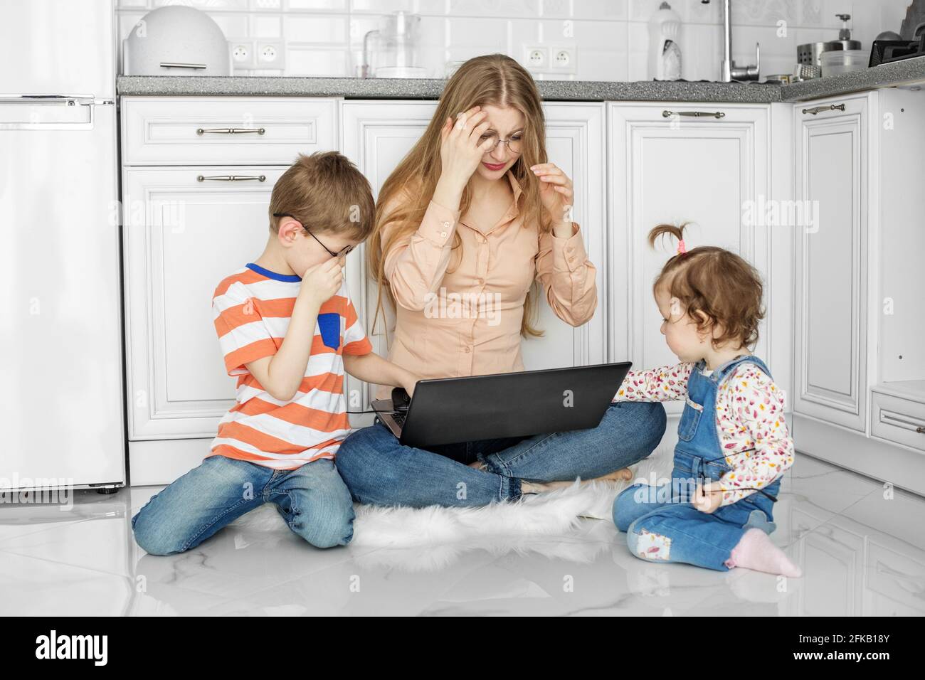 A mother with two children works from home on a computer. Fatigue ...