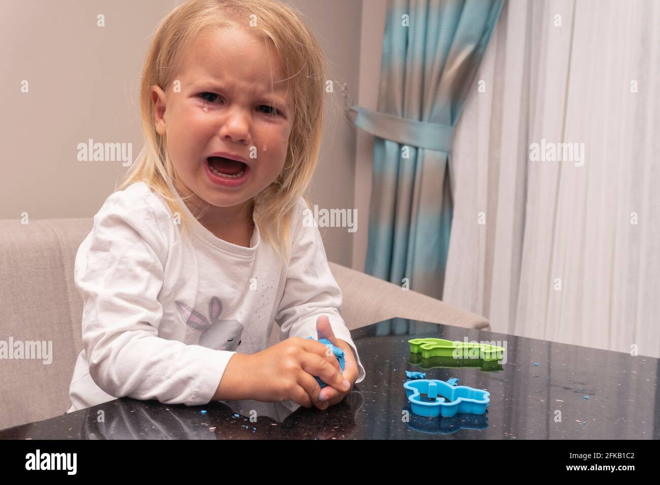 Crying caucasian child plays with colorful play dough Stock Photo - Alamy