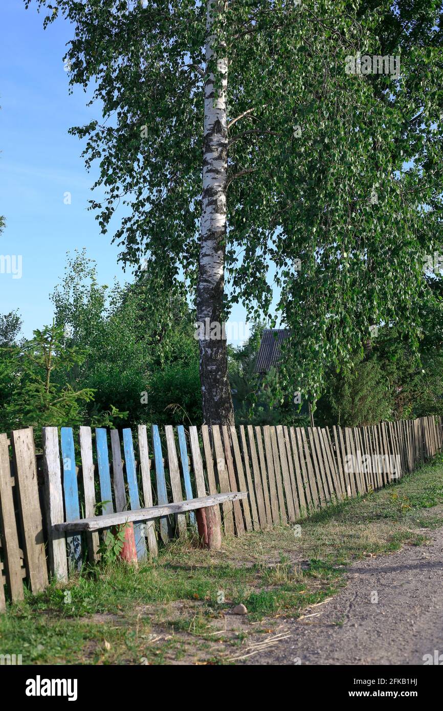 Bench near the fence in the village Stock Photo - Alamy