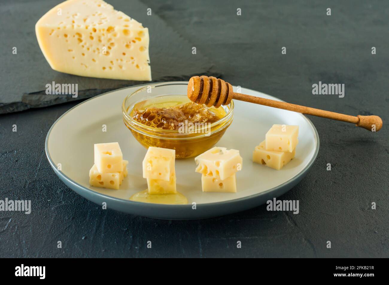 Radamer cheese on a plate served with honey. triangular piece of yellow ...