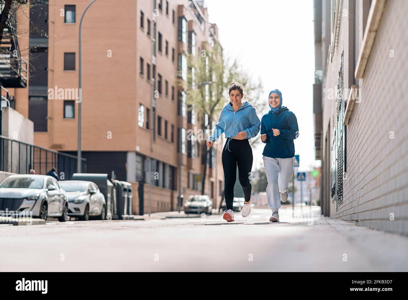 Cheerful muslim woman wearing hijab running in the street with her ...