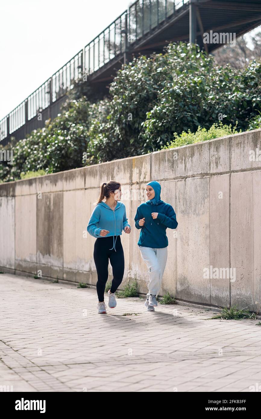Cheerful muslim woman wearing hijab running in the street with her ...