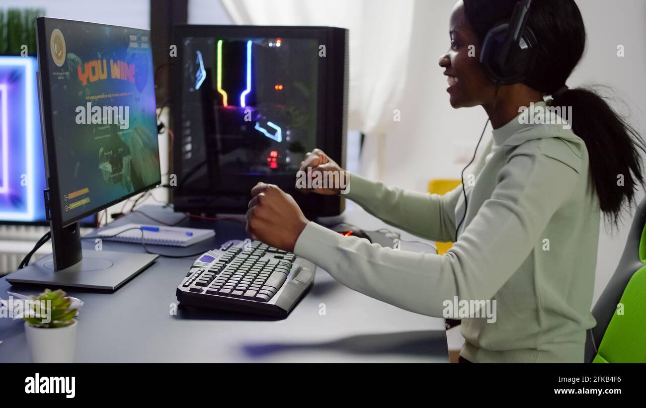 Happy black gamer raising hands winning space shooter online ...
