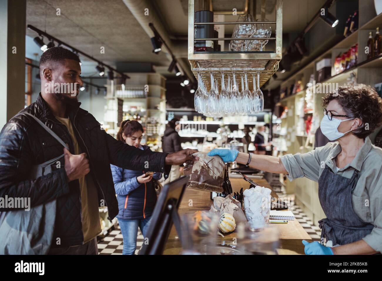 Smiling male customer collecting order from female store owner from ...