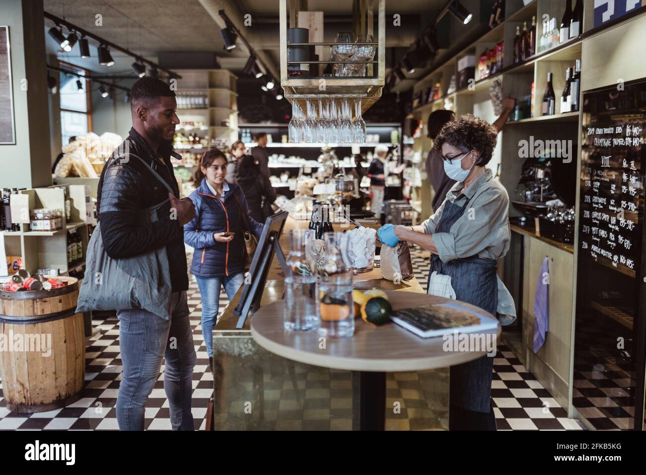 Male and female customer collecting order from store owner during ...