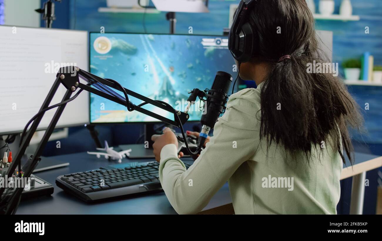 African streamer woman talking with team into headphones and winning ...