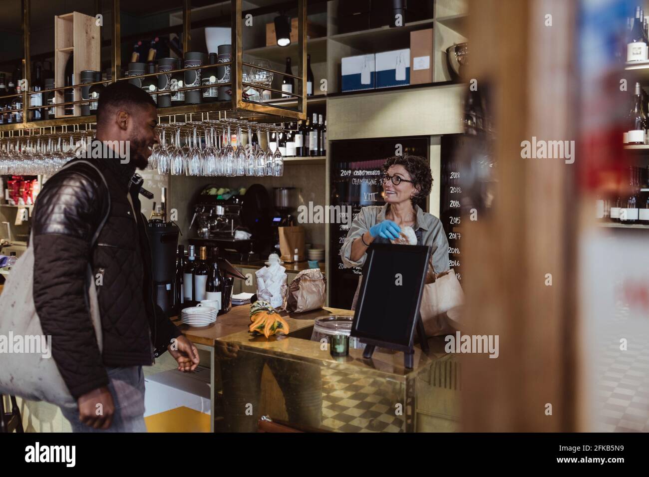 Male customer collecting order from female owner at deli store Stock ...