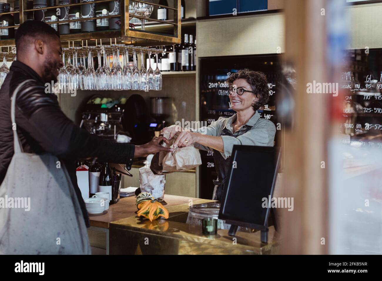 Male customer collecting order from female owner at store Stock Photo ...