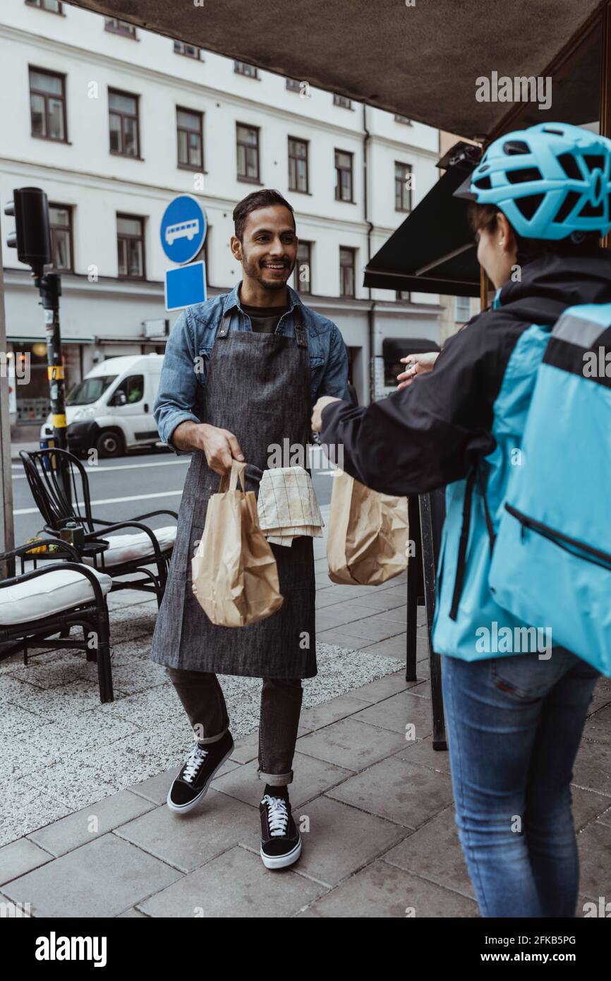 Delivery woman collecting order from male owner while standing on ...