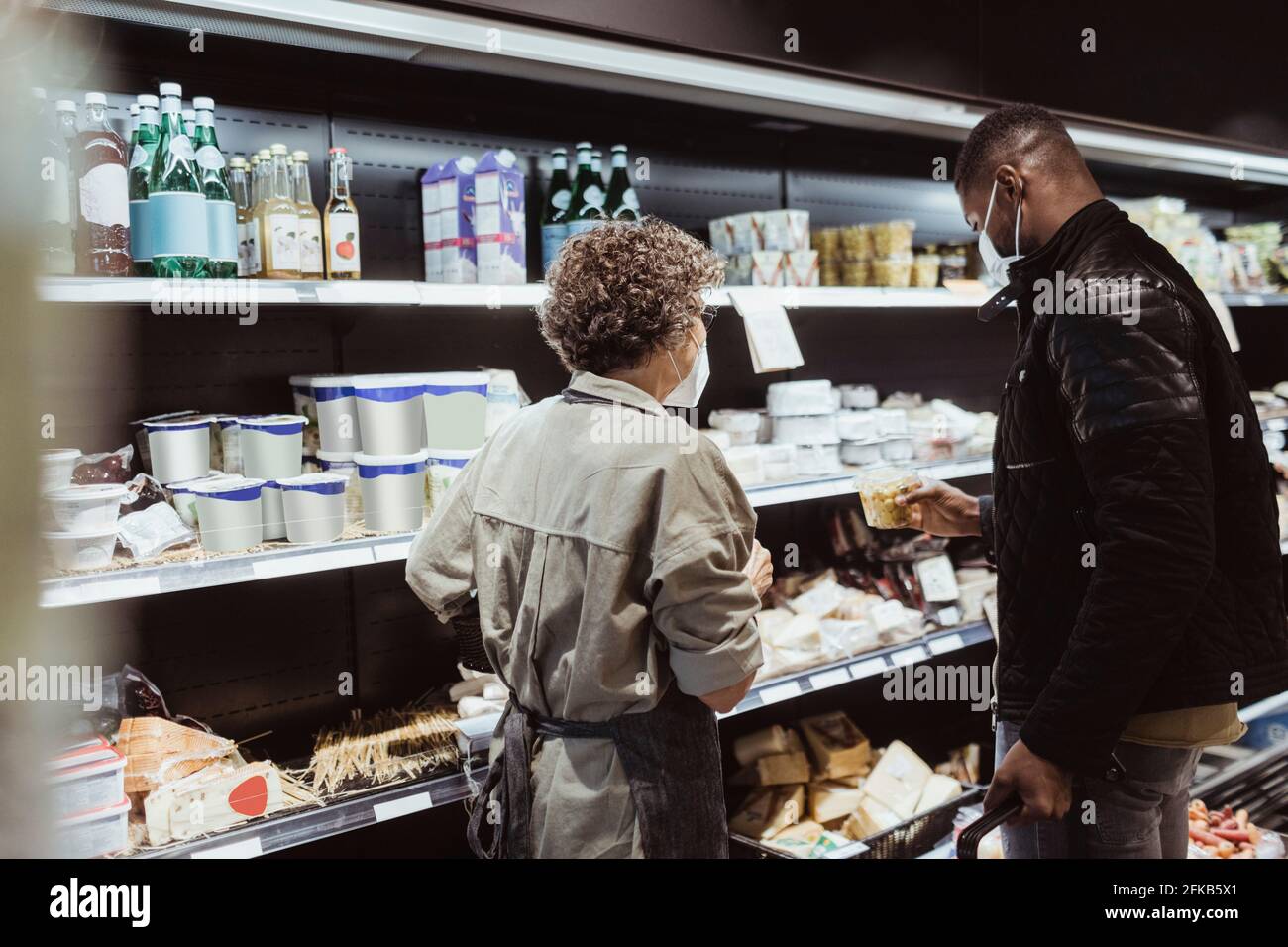 Male customer picking up food product standing by female owner in store ...