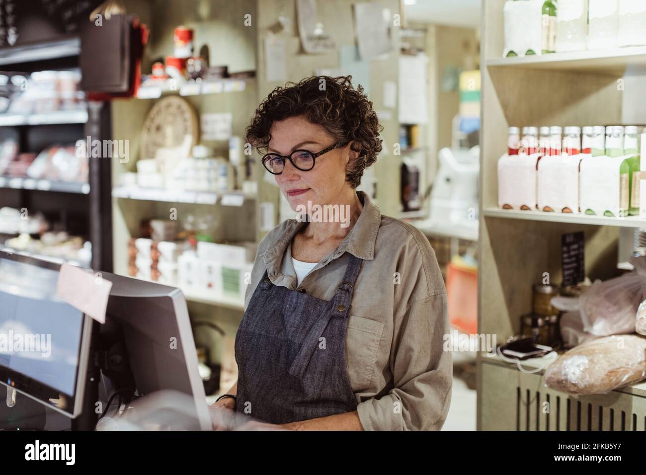 Confident sales woman working on computer in deli store Stock Photo - Alamy