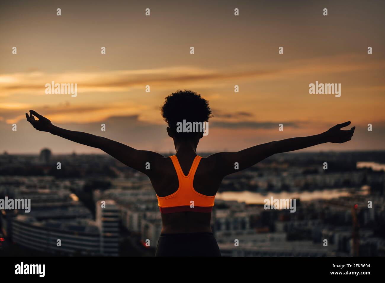 Female athlete with arms outstretched exercising during sunset Stock ...