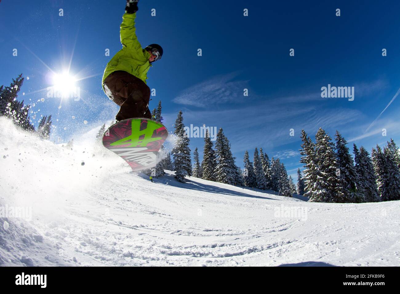 A man flying through the air while riding a snowboard down a snowy hill ...