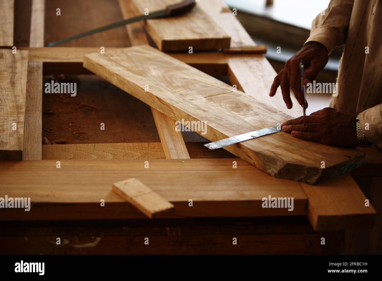 Carpenter is making a panel door frame of teak wood in a room of under ...