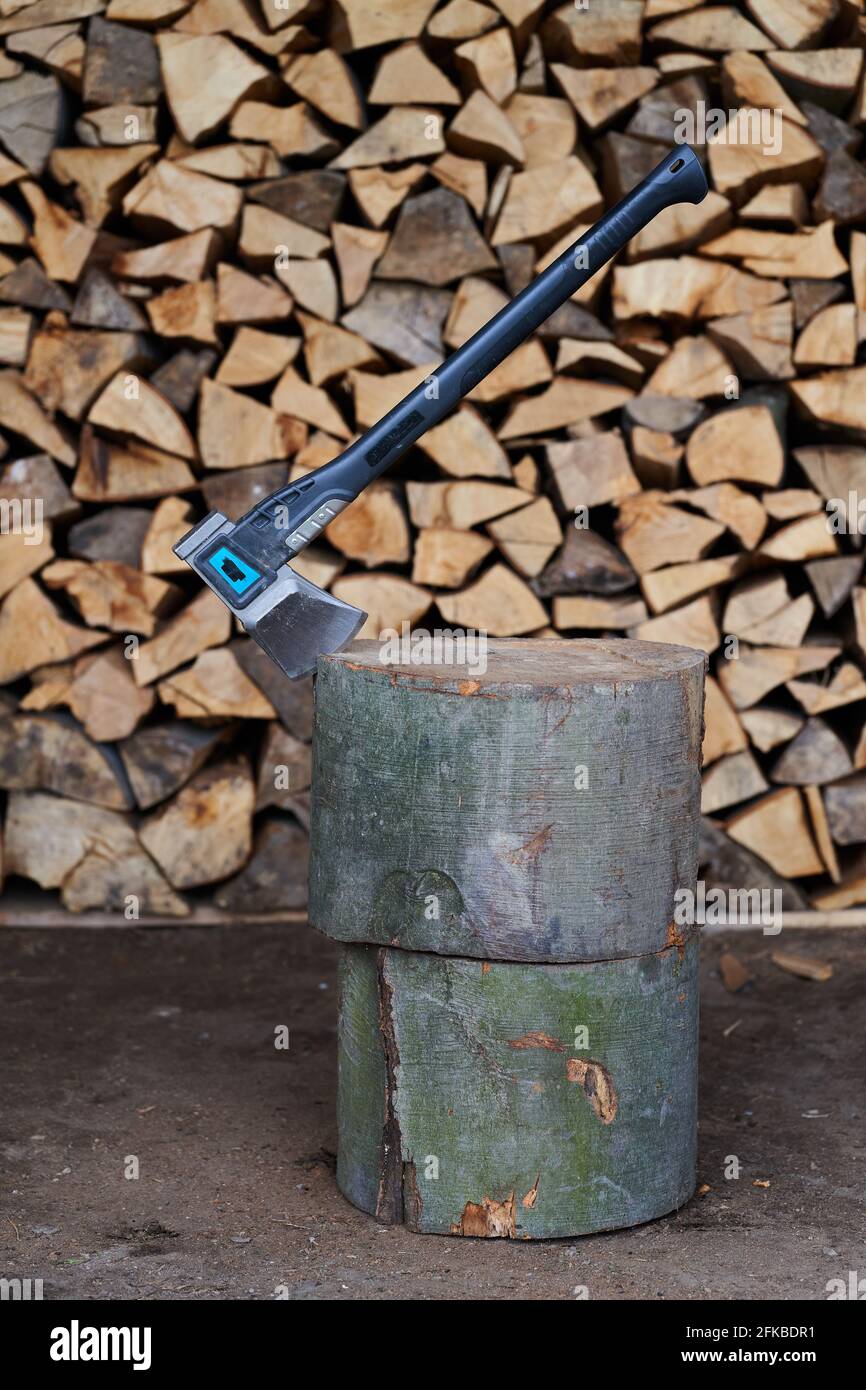 Heavy splitting axe in a stump by a stack of firewood Stock Photo - Alamy