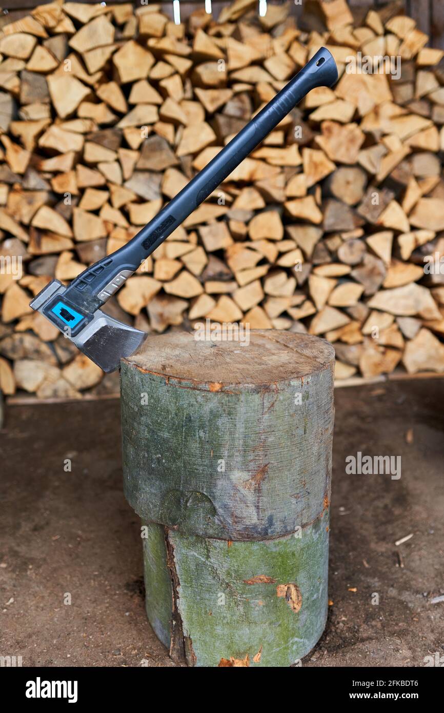 Heavy splitting axe in a stump by a stack of firewood Stock Photo - Alamy