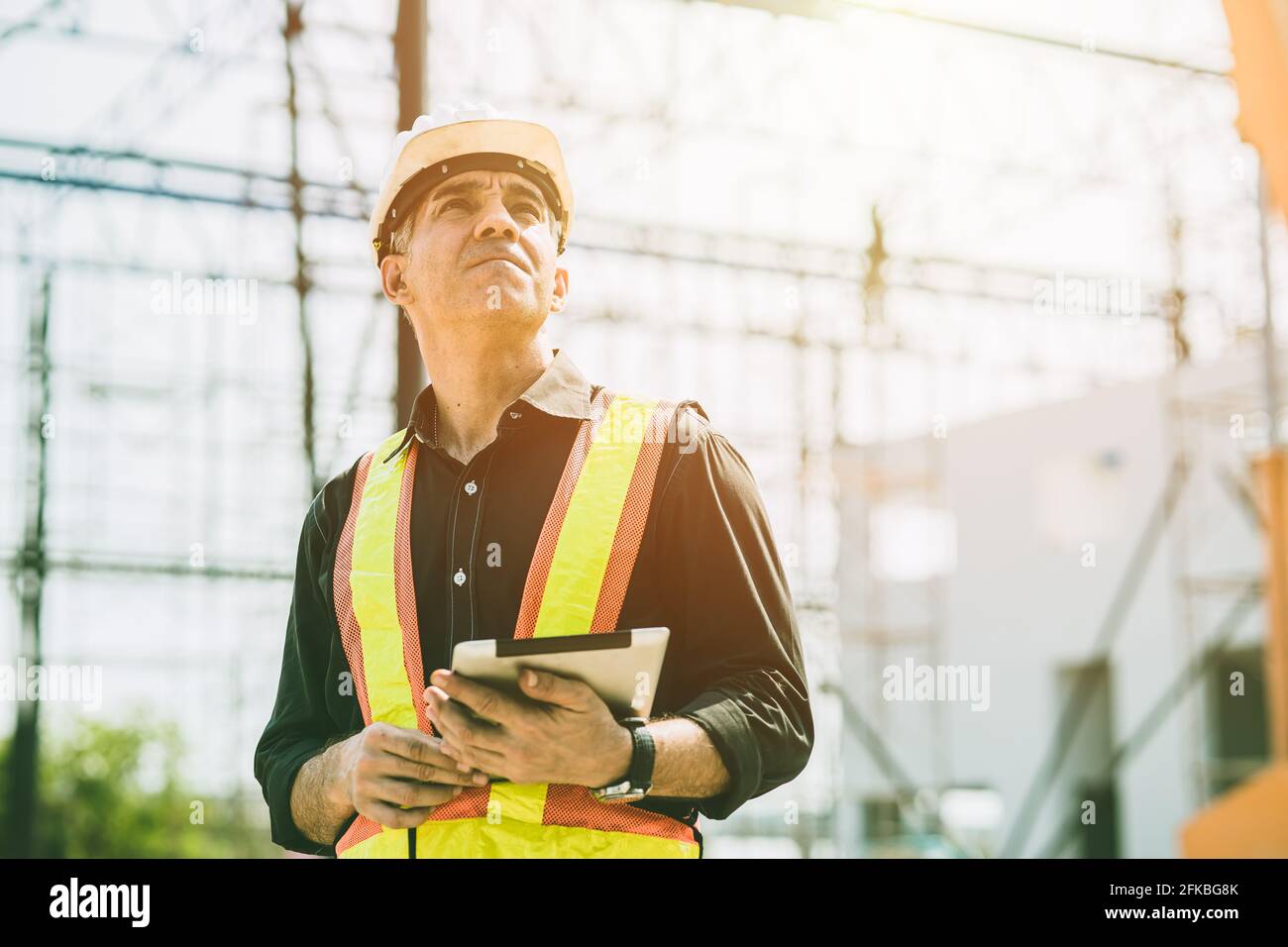 Foreman builder engineer worker looking at large building construction ...