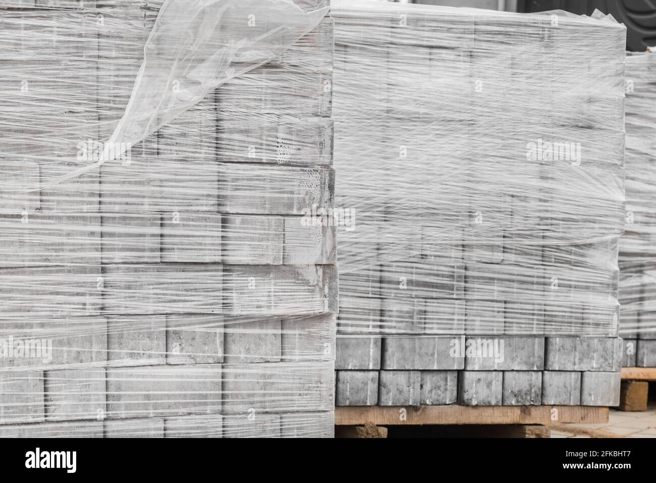 A pile of new paving slabs on a wooden pallet wrapped in plastic wrap ...