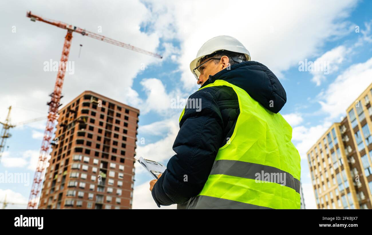 Consulting engineer at construction site holding blueprint in hand ...