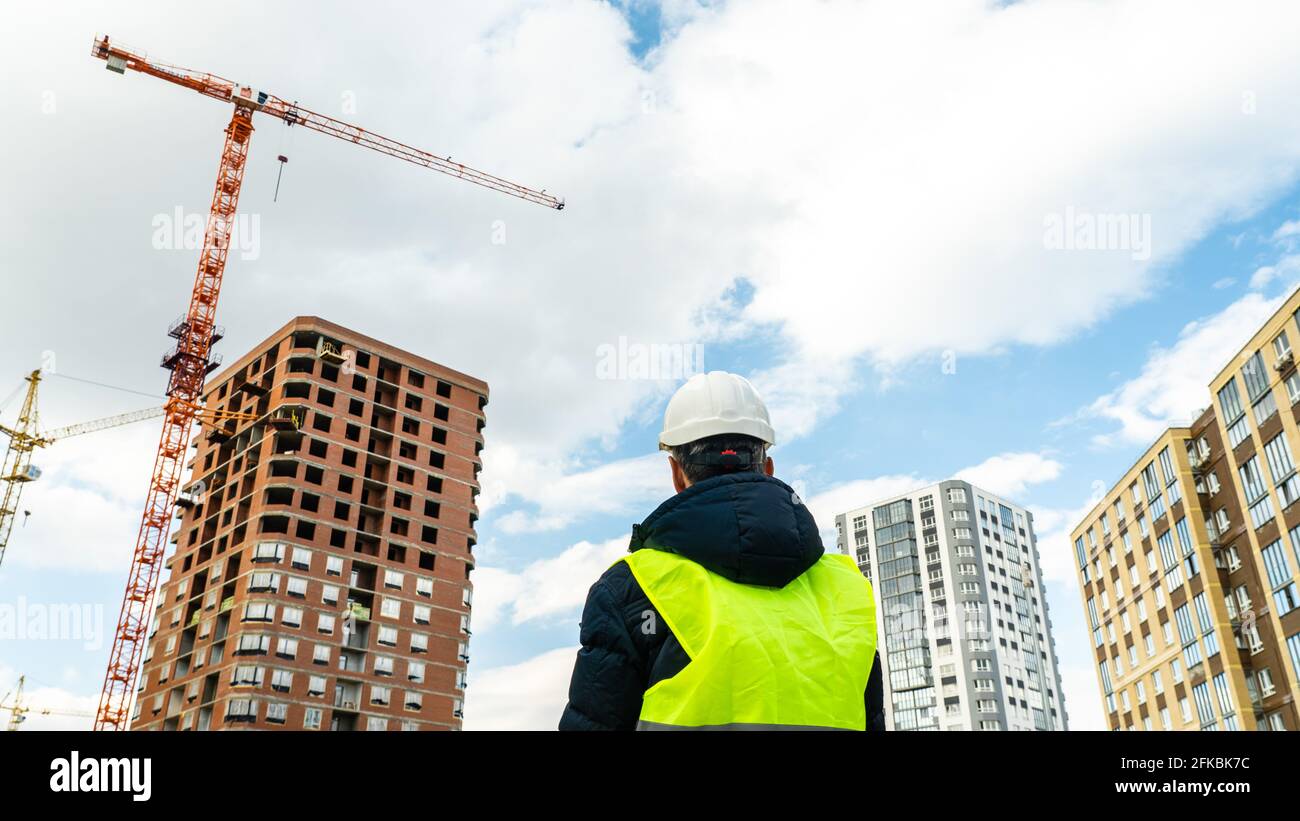 Consulting engineer at construction site holding blueprint in hand ...