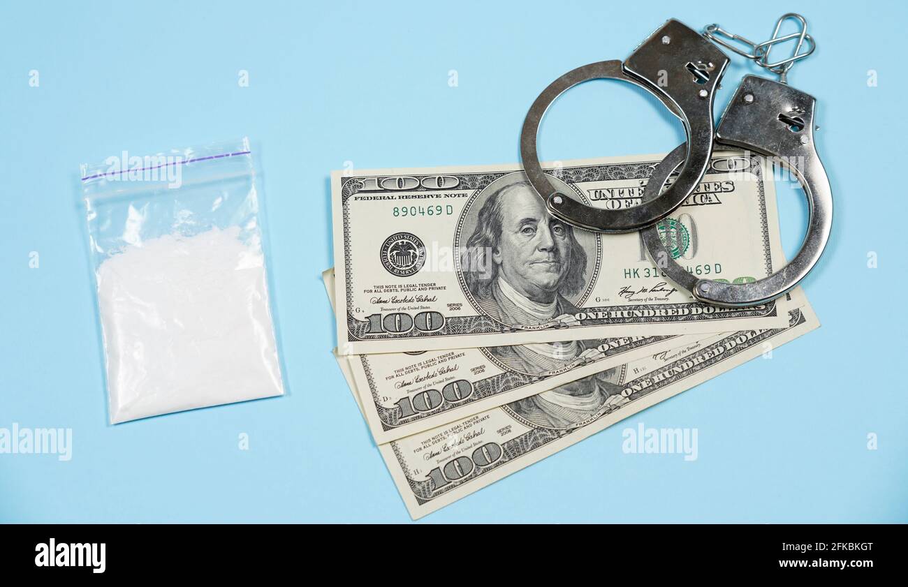 A bag of drugs, US dollars and handcuffs on the table. Concept ...