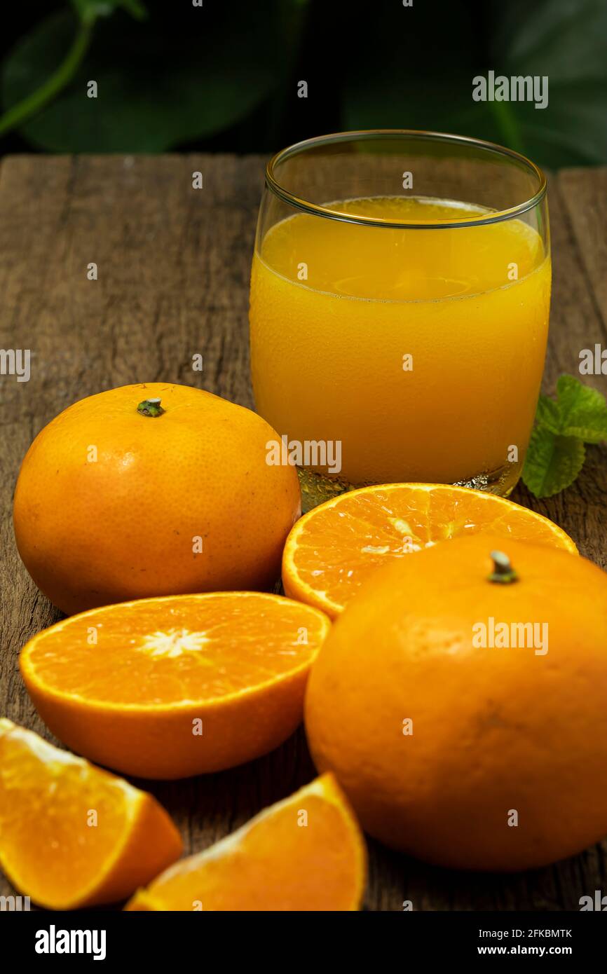 A glass of orange juice with orange fruit cut in half and orange slice ...