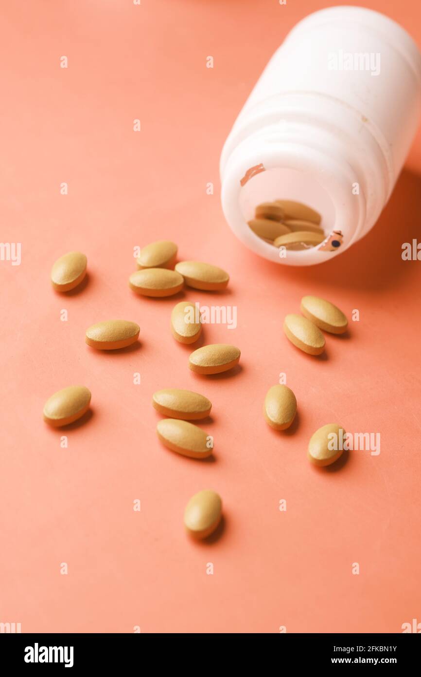 herbal medicine spilling from a container on orange background Stock ...