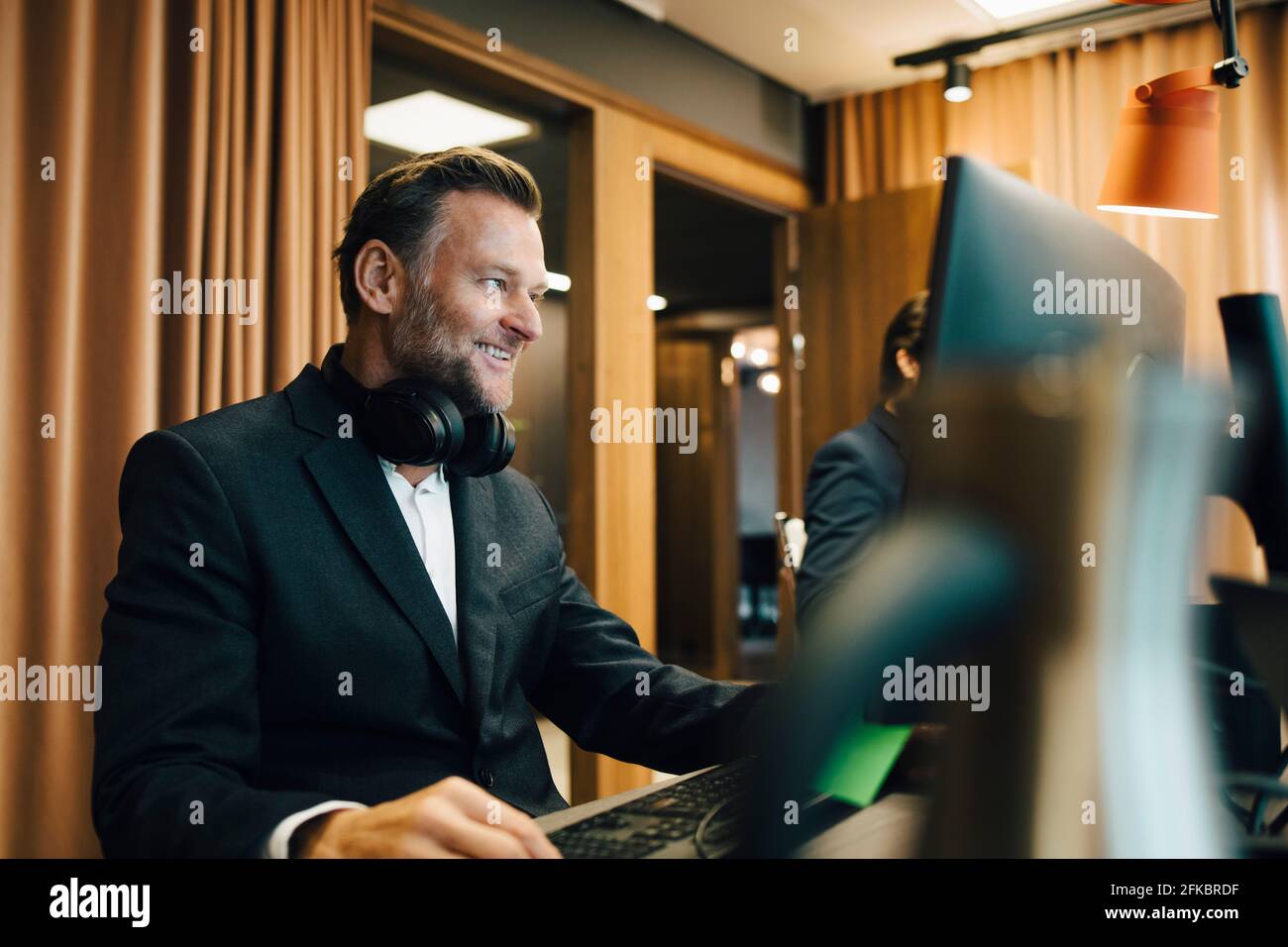 Smiling male entrepreneur working on computer in office Stock Photo - Alamy