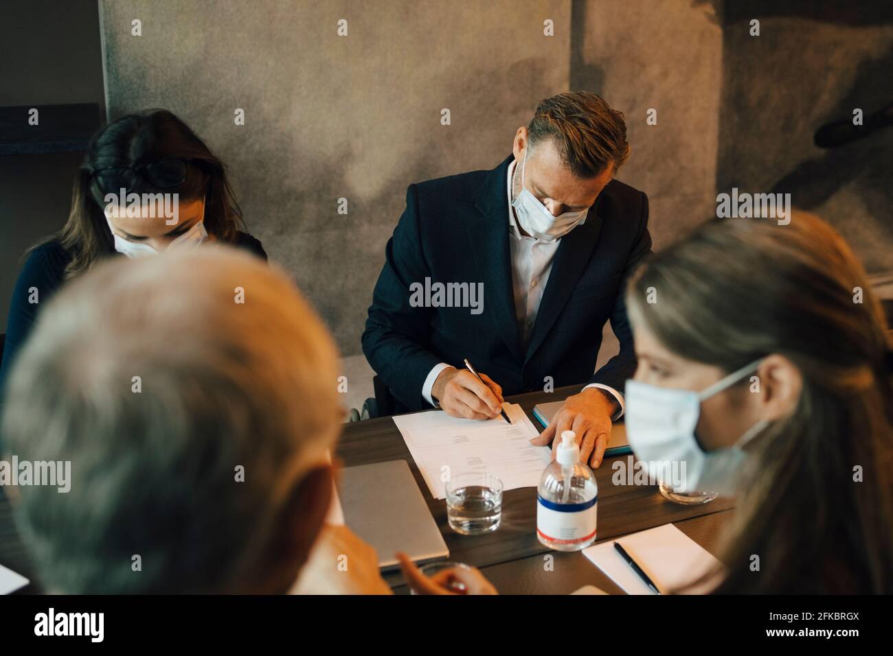 Business people discussing over document during meeting at board room ...