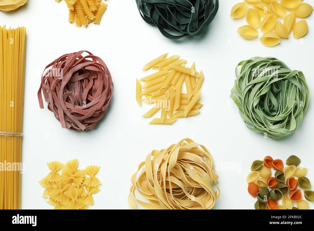 Different uncooked color pasta on white background Stock Photo - Alamy