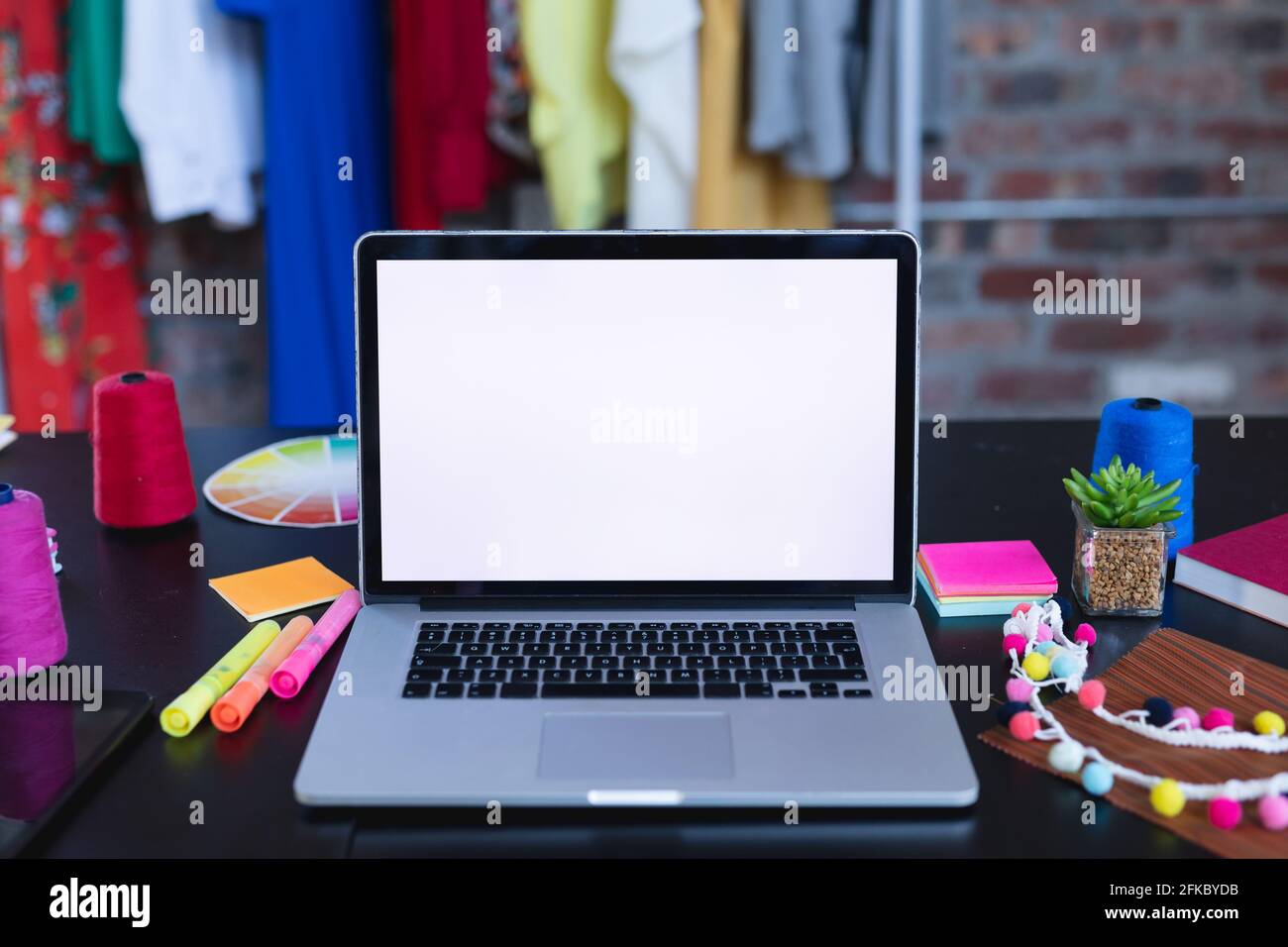 Laptop with copy space on screen lying on desk full of designers ...