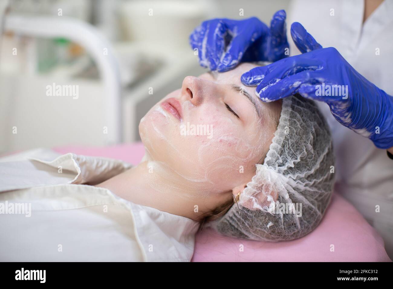 Cosmetologist hands in blue gloves touching face of caucasian teen girl ...