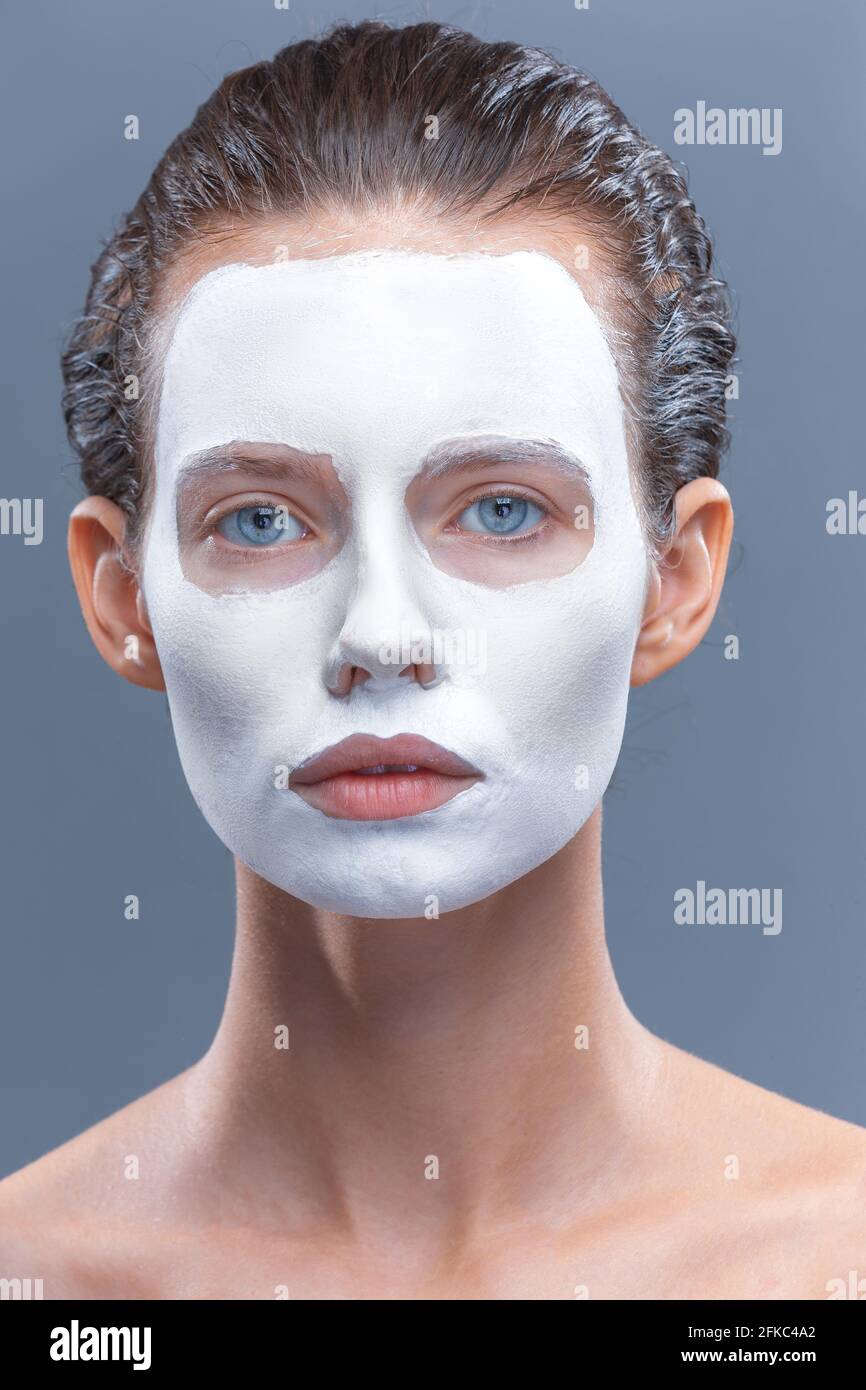 Beautiful girl is applied a white cosmetic mask from black dots ...