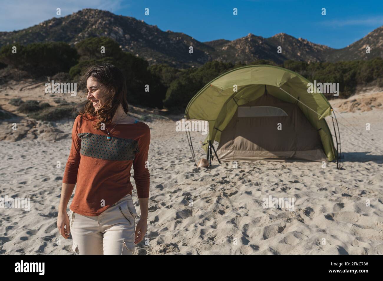 Attractive young woman walking on the beach during a camping in a windy ...