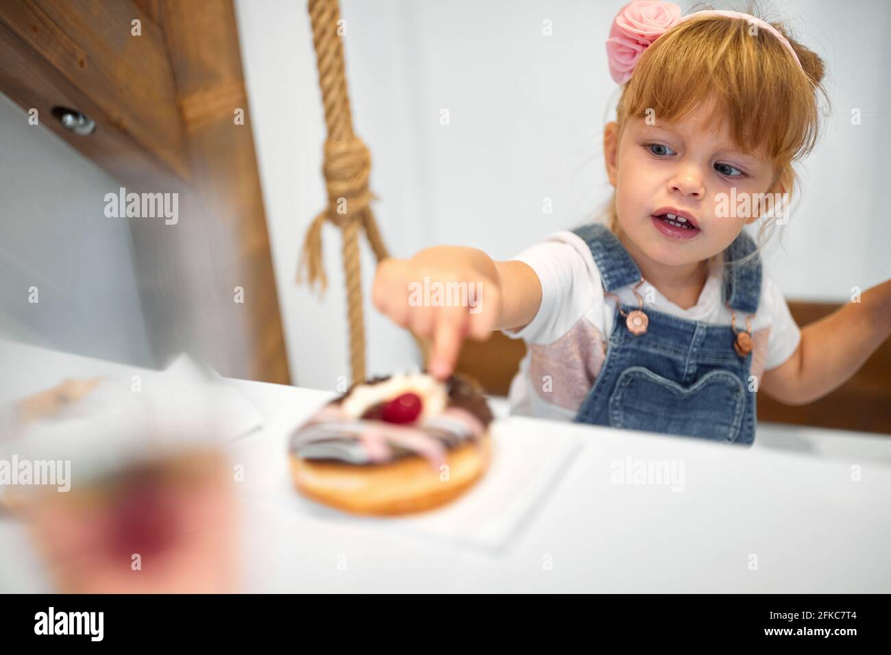 A little girl in a pastry shop is amazed by delicious donut of ...