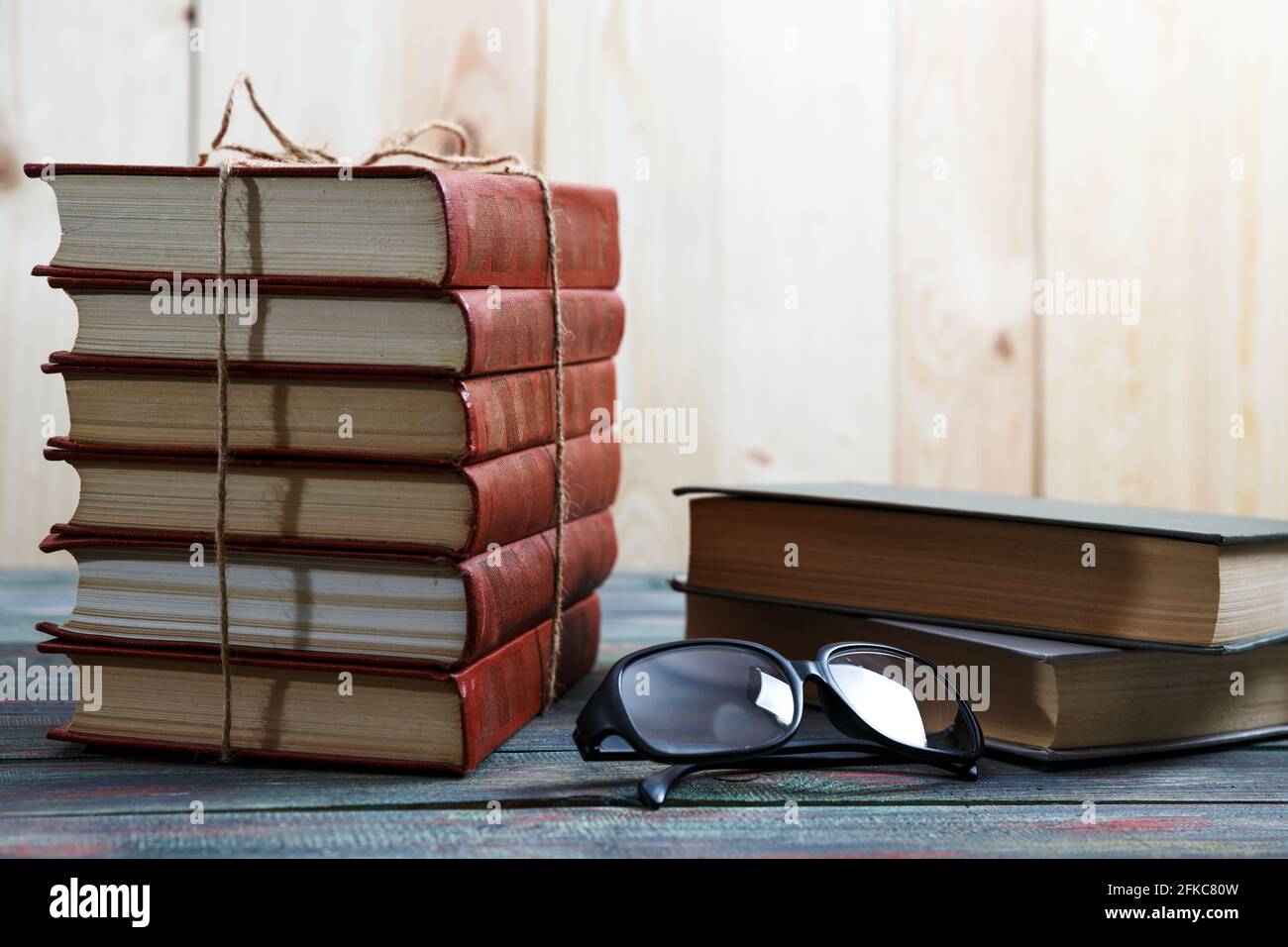 Books stacked on wooden desk in university or public library room or ...