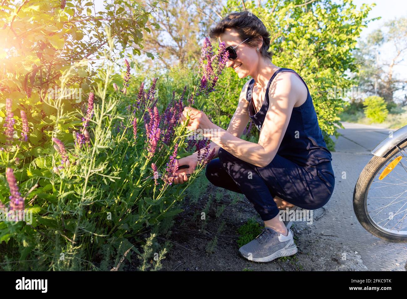 Portrait of young adult happy caucasian woman gathering sage herbs wild ...