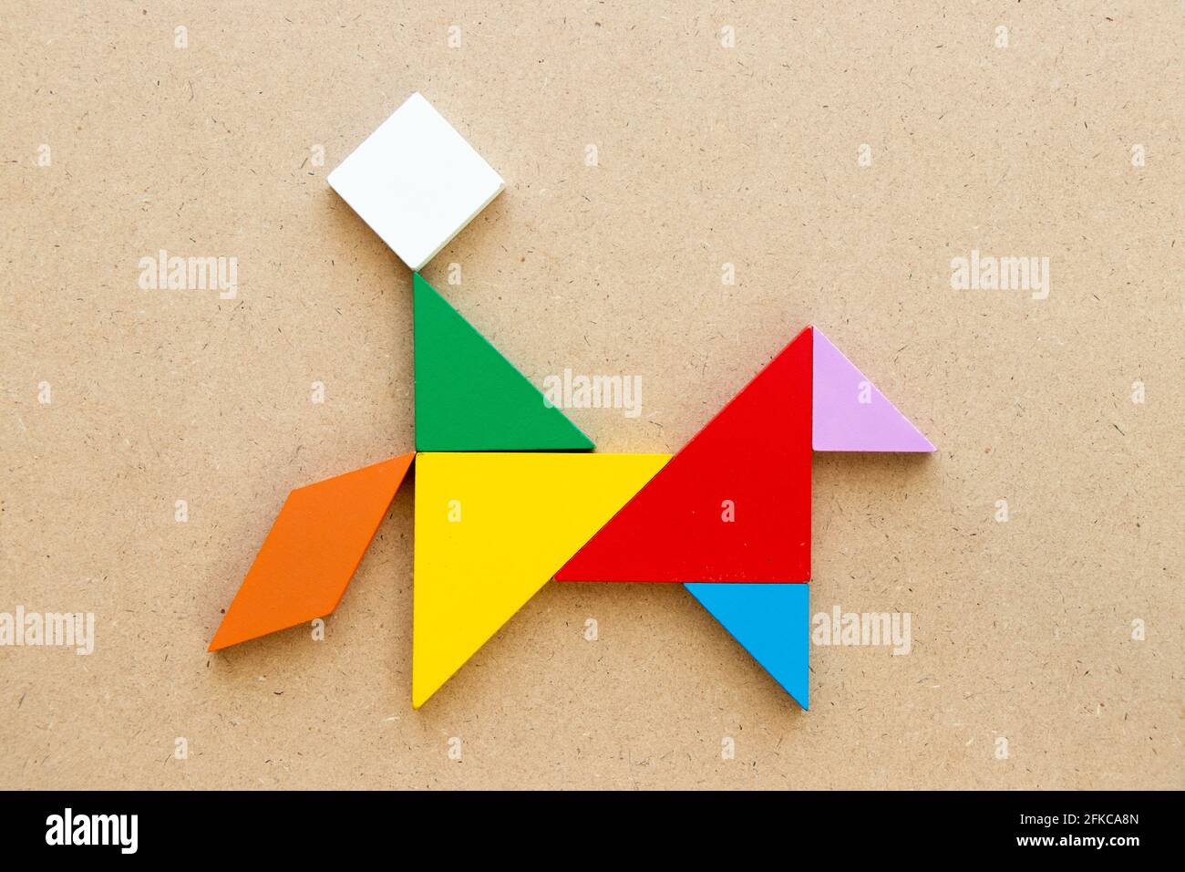 Color tangram puzzle in man ride the horse shape on wood background ...