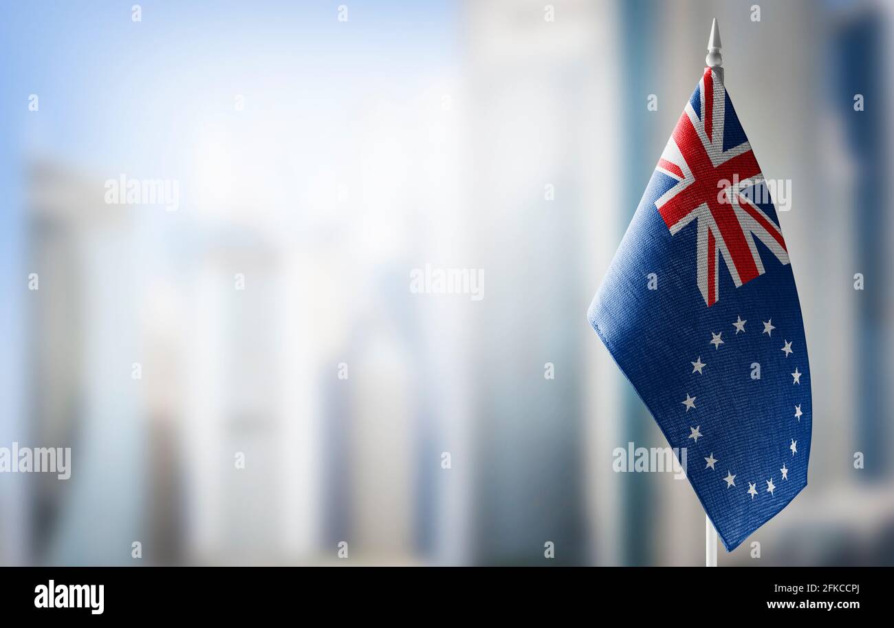 A small flag of Cook Islands on the background of a blurred background ...