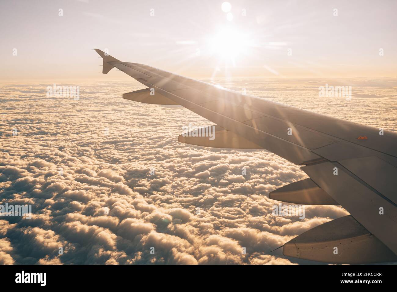 Sun shines brightly on the clouds under the wing of the plane. View ...