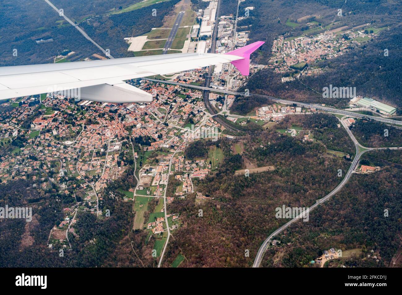 View from the window of a flying plane on the city, roads, green forest ...