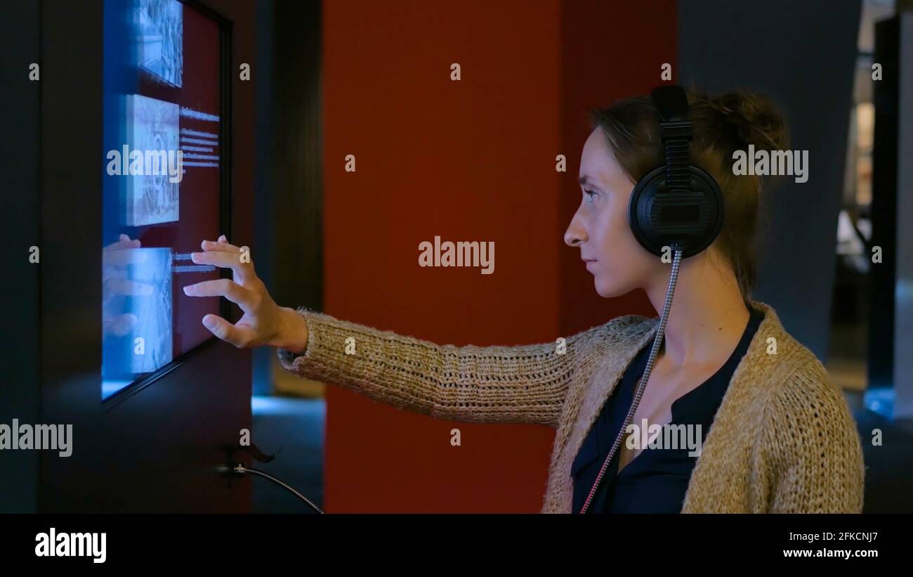 Woman using headphones and listening audio guide Stock Photo - Alamy