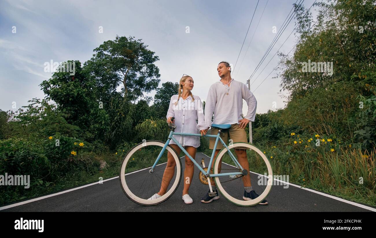Biking road trip. Love couple on blue bike in white clothes on forest ...