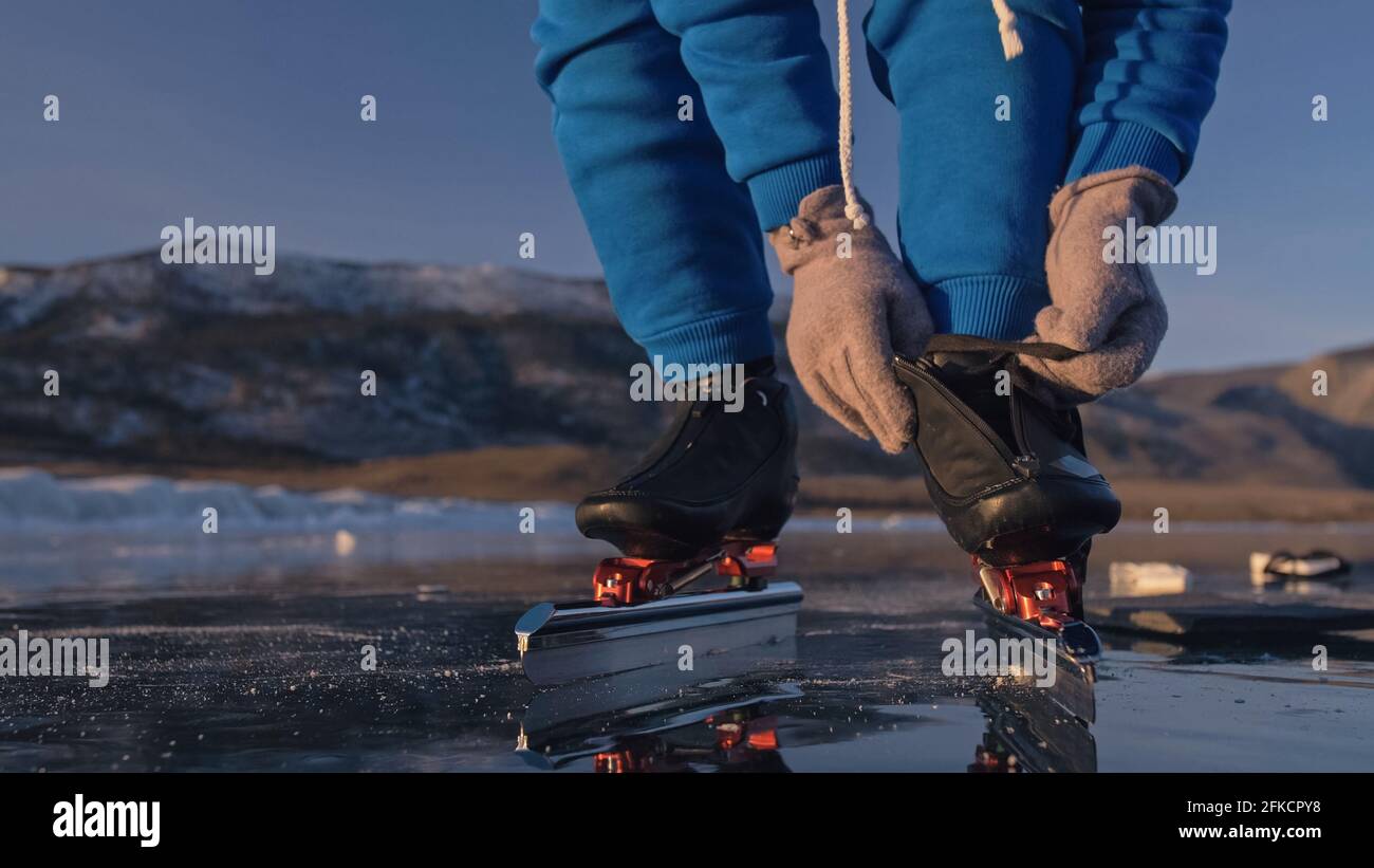 The child train on ice speed skating. Athlete puts on skates. The girl ...