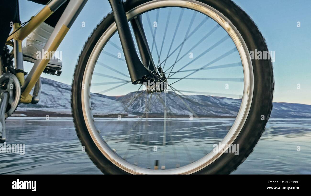 Woman is riding bicycle on the ice. Tires on bike are covered wi Stock ...