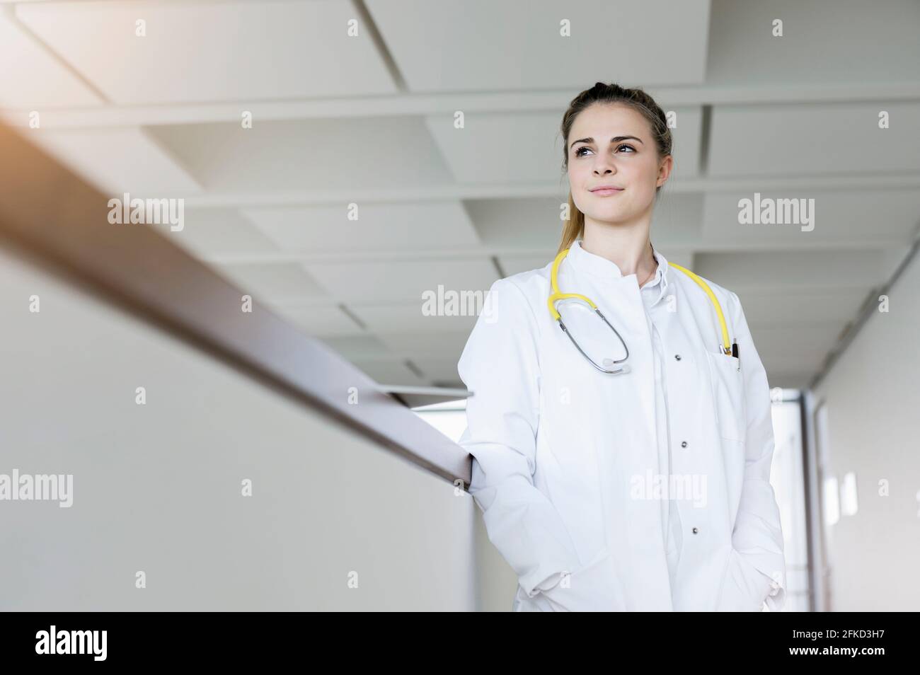 Germany, Bavaria, Munich, Young female doctor standing in corridor ...