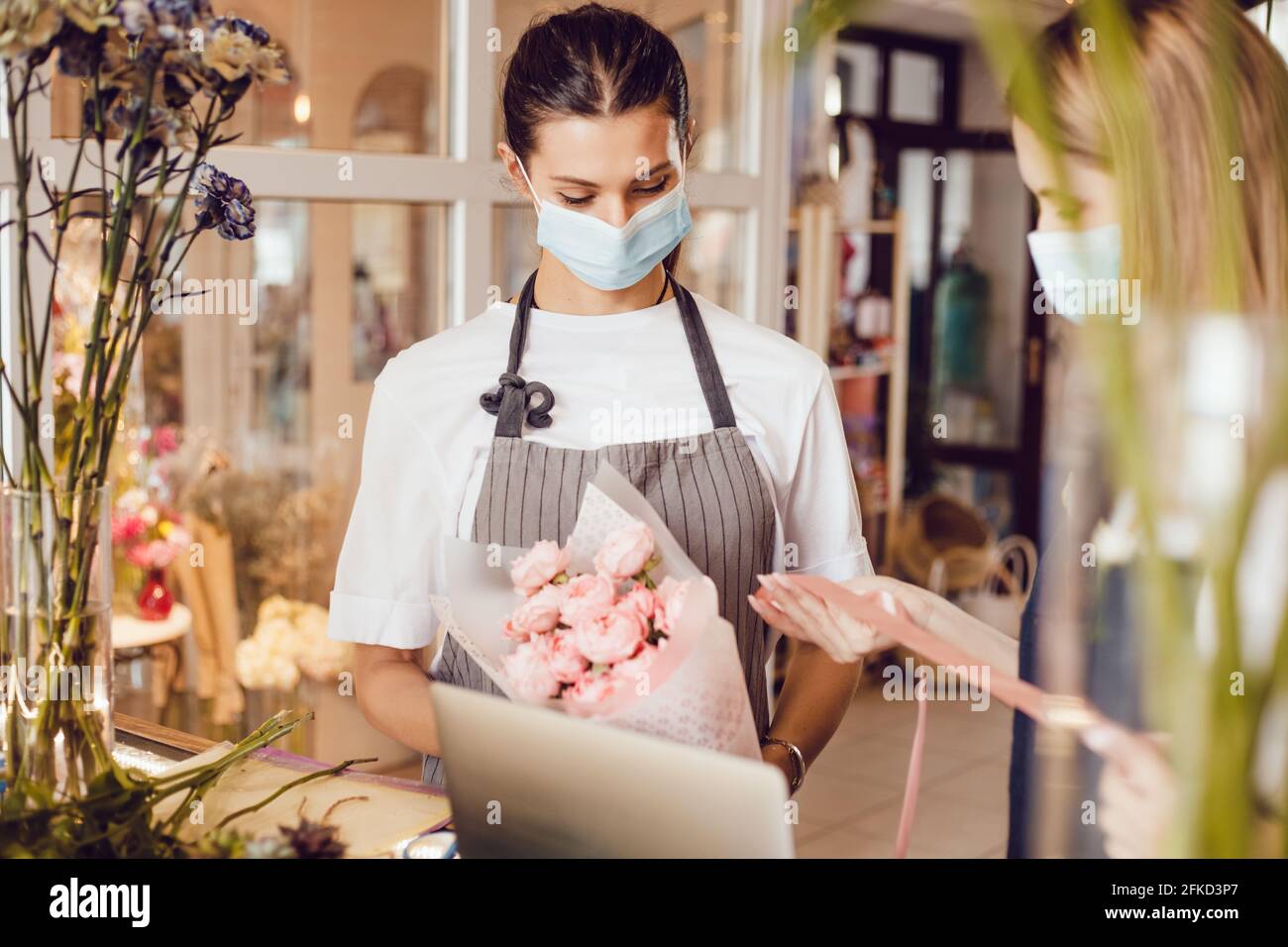 Flower shop workers in protective masks decorate a bouquet Stock Photo ...