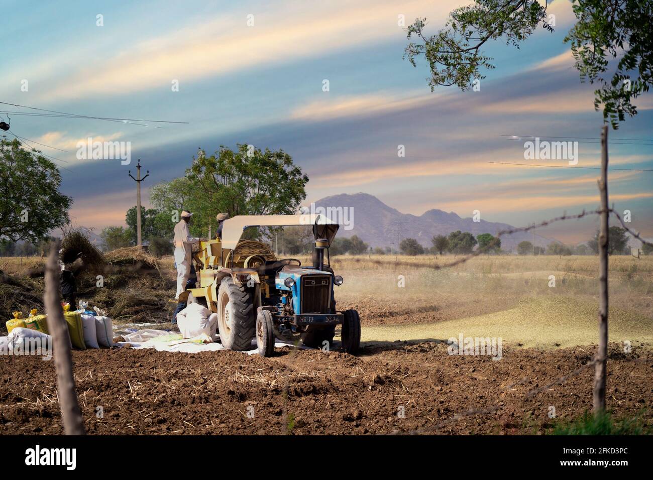 farmers in traditional clothes loading grain into a tractor where it is ...