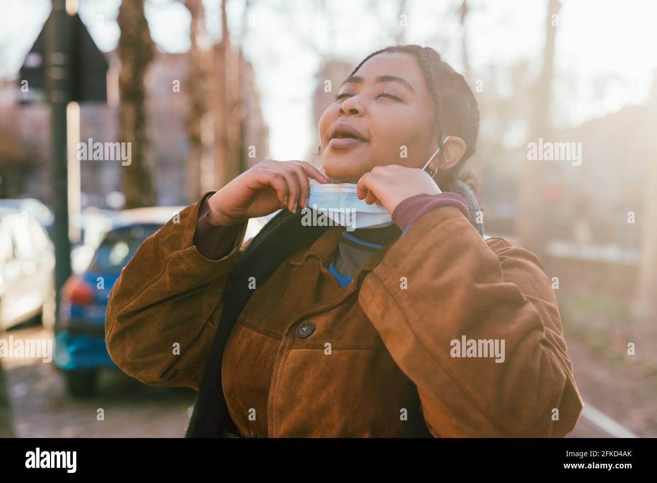 Young woman removing face mask outdoors Stock Photo - Alamy