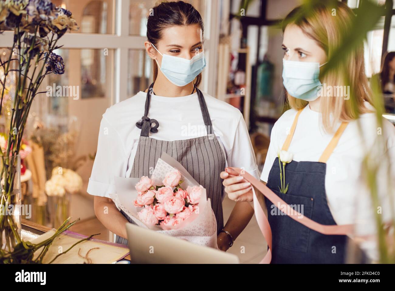 Flower shop workers in protective masks decorate a bouquet Stock Photo ...